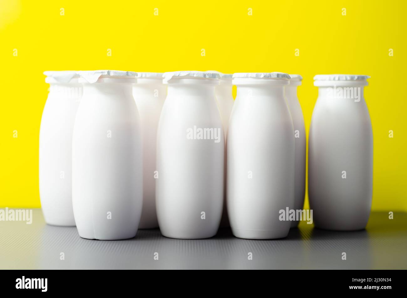 White plastic yogurt bottles on yellow background, typical packaging ...