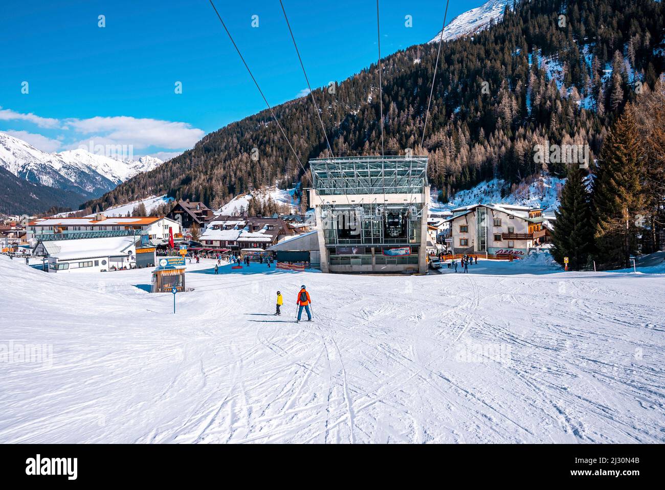Skiers skiing towards station on snowy mountain in alps with dense ...