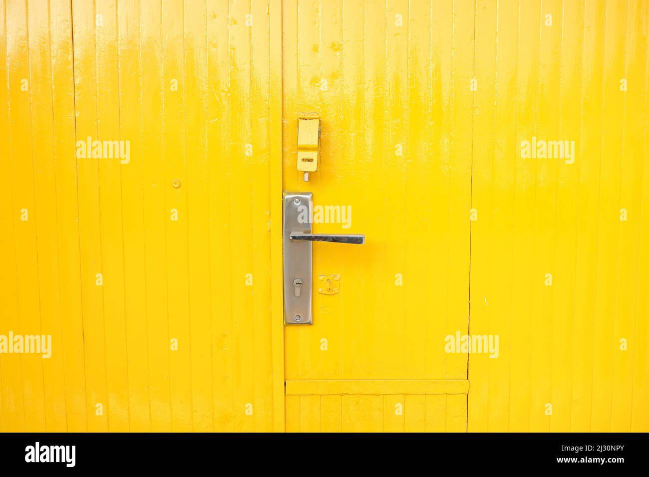 A bright yellow gate background with a silver, metal handle Stock Photo ...