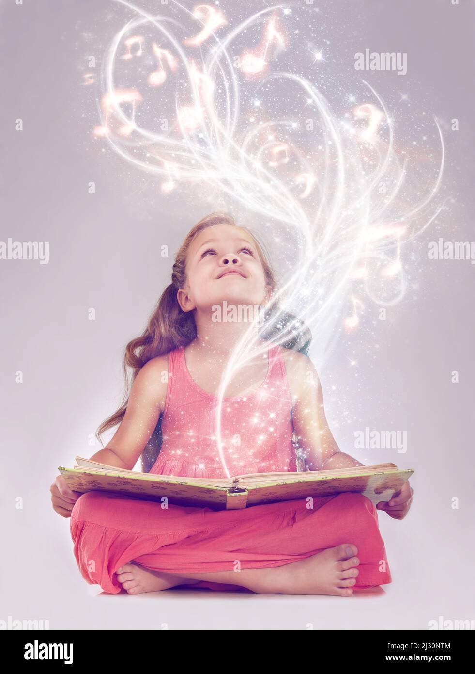 Imagination running wild. Studio shot of a young girl reading a ...
