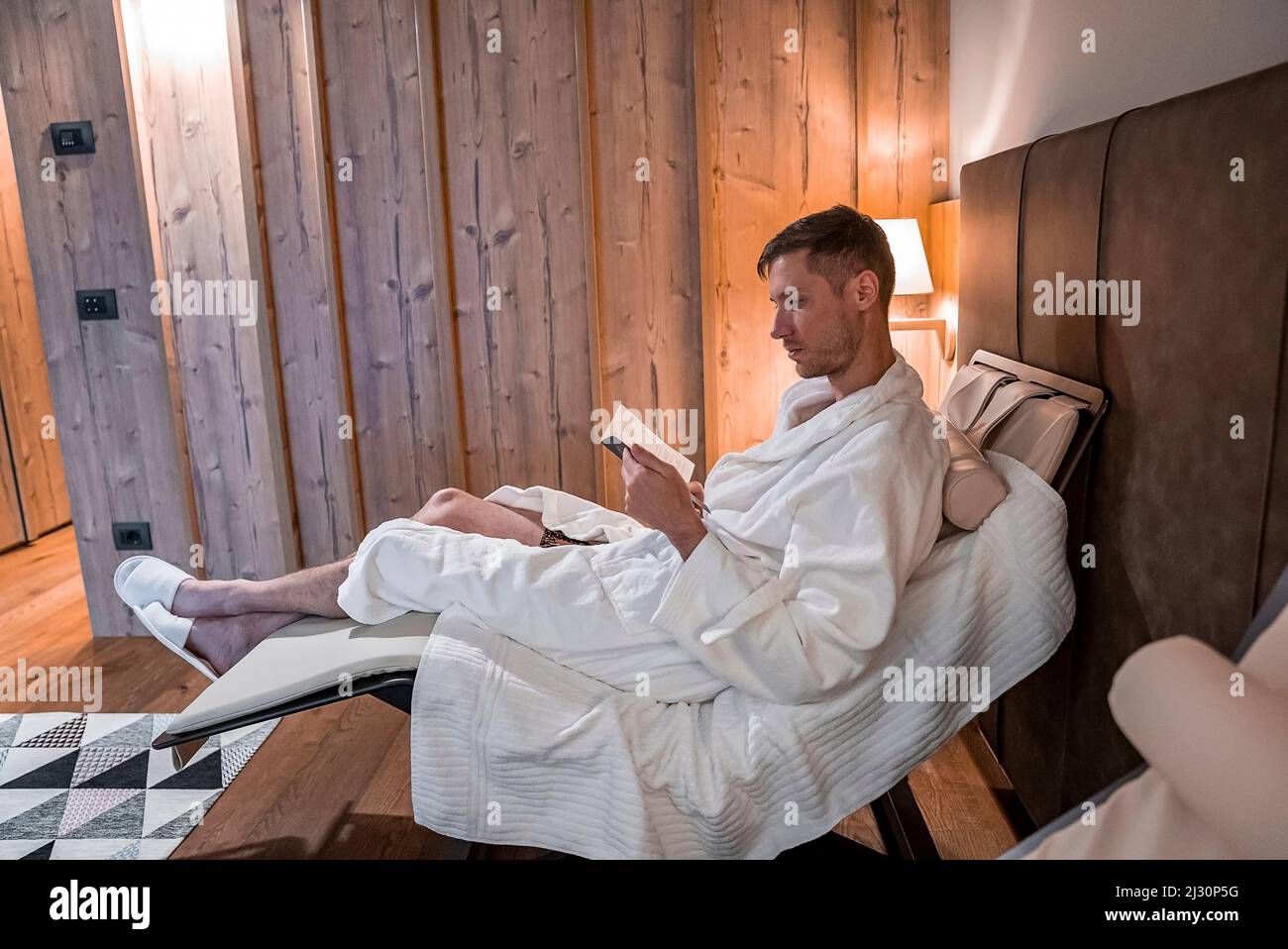 Man wearing bathrobe relaxing on reclining chair at resort Stock Photo ...