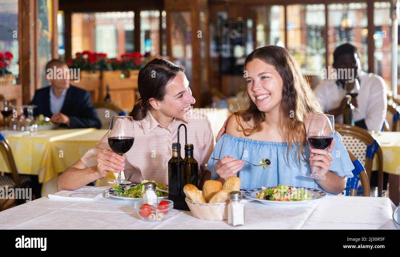 Two positive female best friends drinking wine in restaurant Stock ...