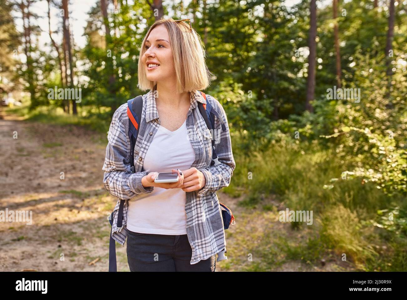 Woman navigate with mobile phone while walking in the woods during ...