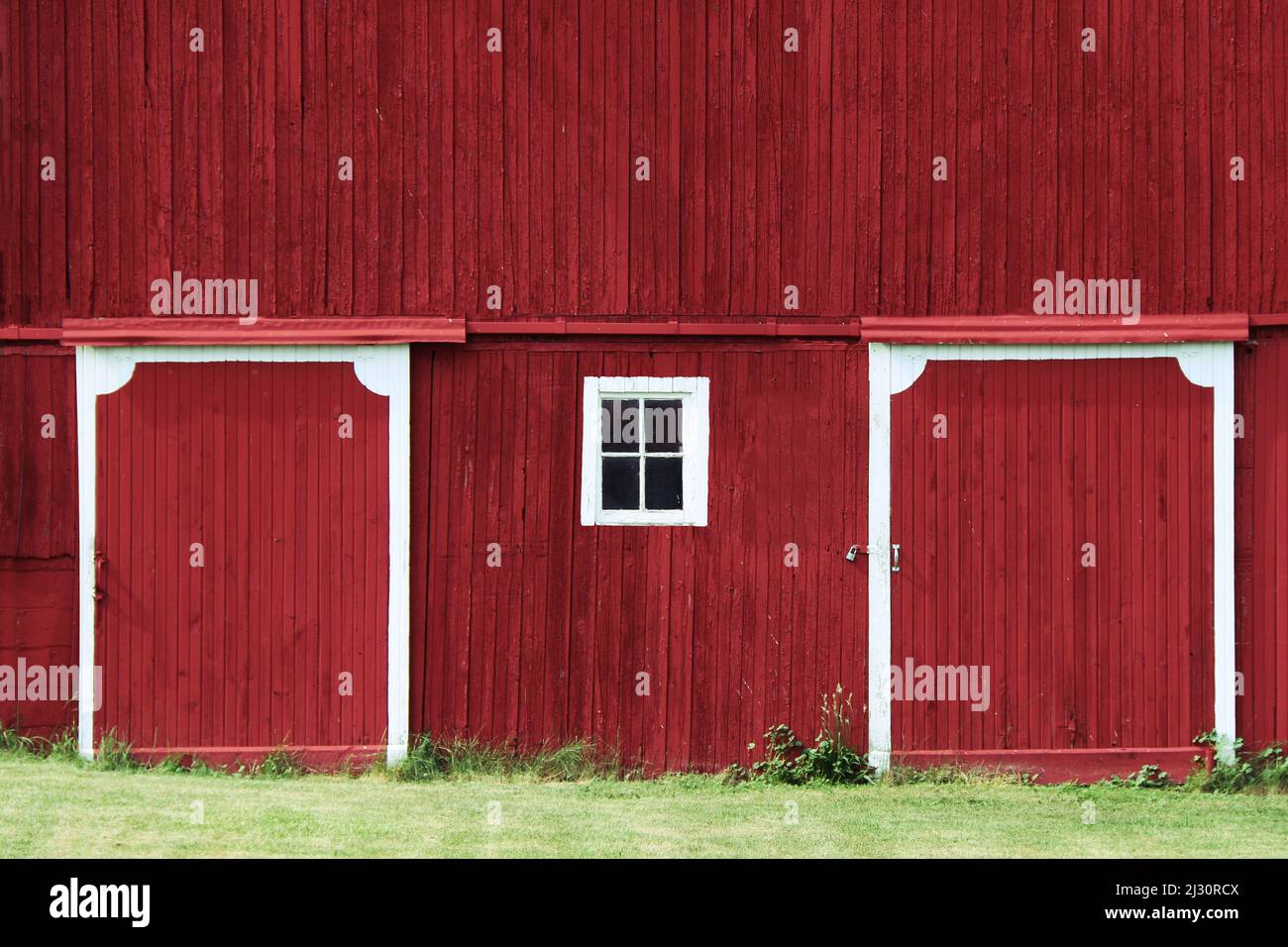 a red farm barn hanging doors shadows trees overcast sunny green grass ...