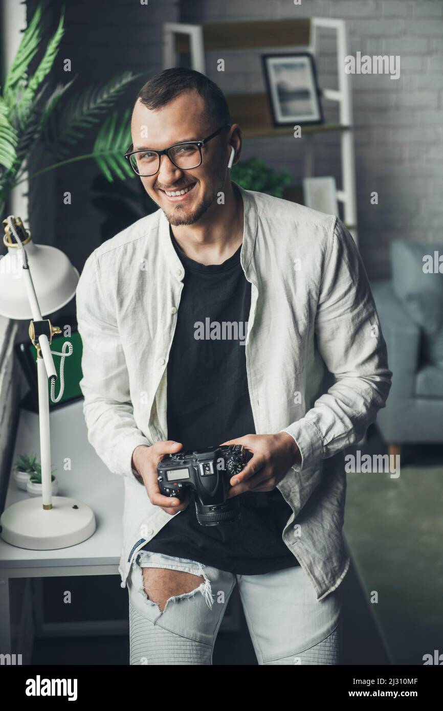 Portrait of a professional photographer standing against working desk ...