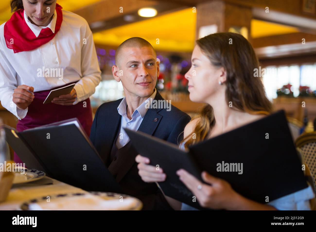 Positive young couple making order at restaurant Stock Photo - Alamy