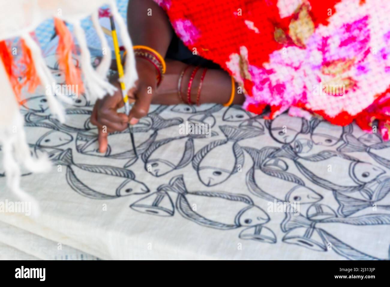Blurred image of young Bengali female artist painting fishes ...