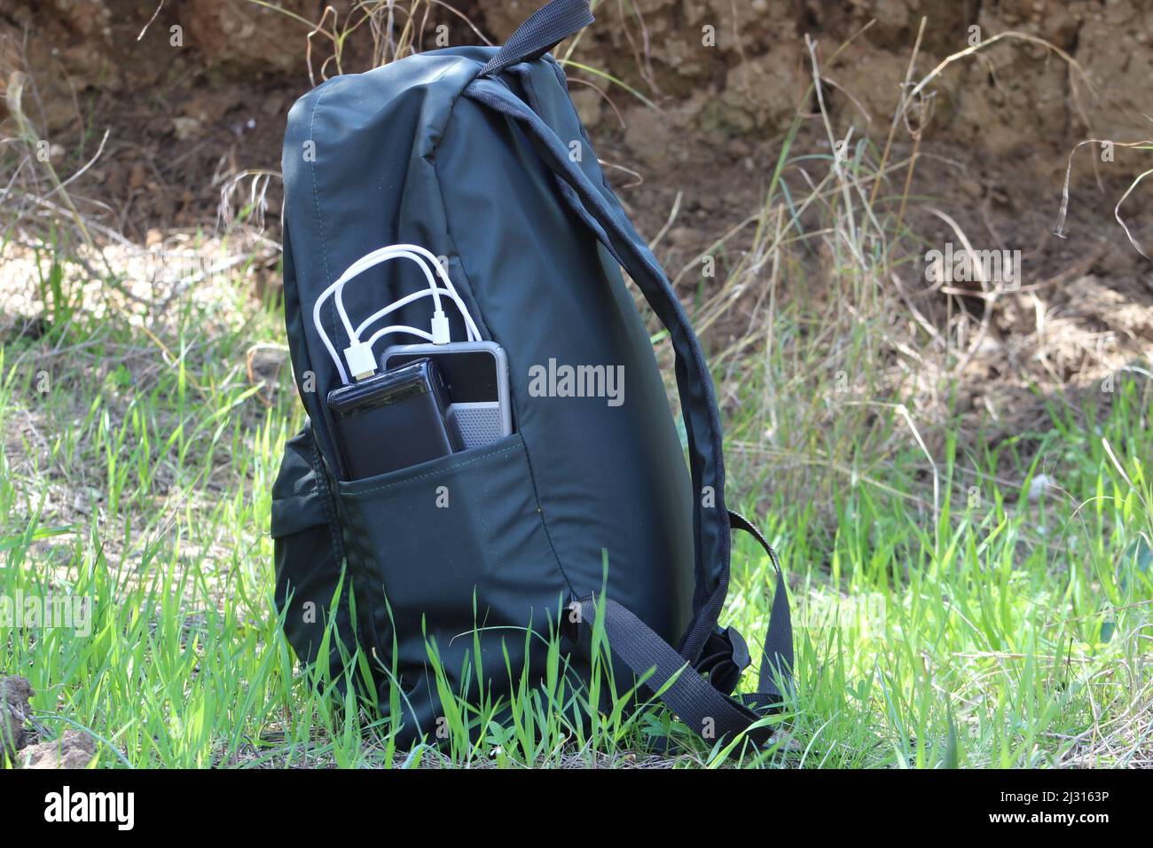 Smartphone charged with black power bank in green backpack. Close up ...