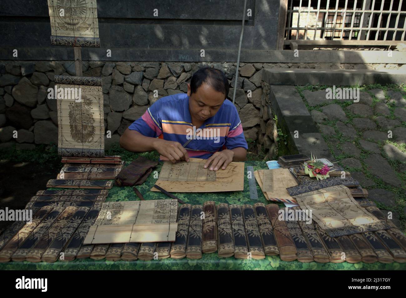 Balinese artist making artwork on lontar leaves in traditional village ...