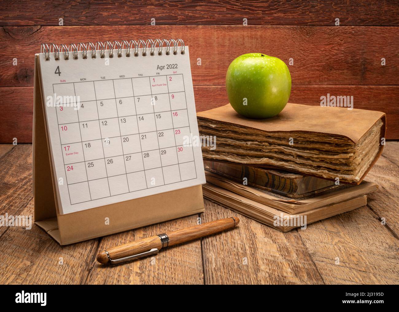 April 2022 - spiral desktop calendar with old book or journal and apple ...