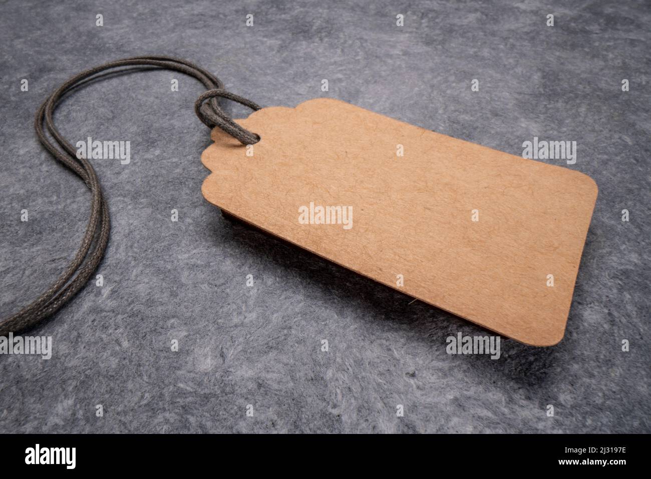 blank paper price tag with a twine against gray textured handmade paper ...