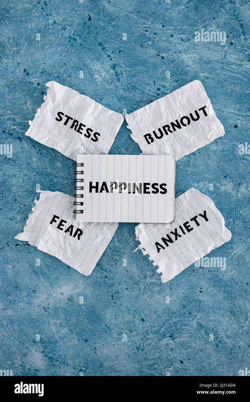 Happiness text on notepad with Fear Anxiety Stress and Burnout words on ...