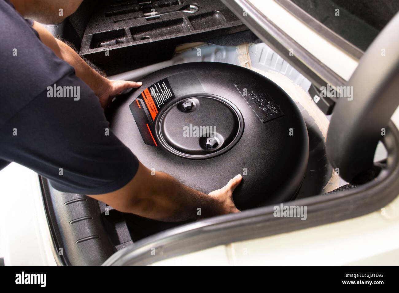 A mechanic is installing a car donut-shaped LPG tank in a spare wheel ...