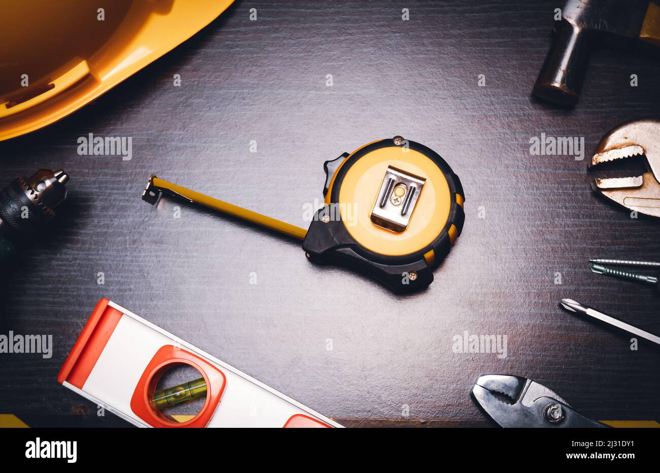 Measuring tape on wooden table background with mechanic tools alongside ...