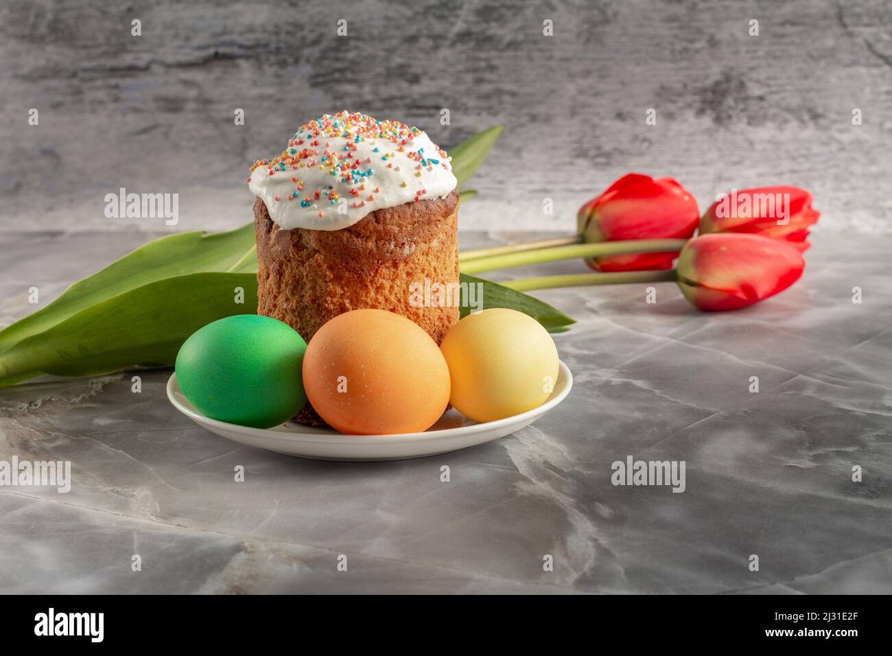 Easter cake and colorful Easter eggs on a plate with tulip flowers ...