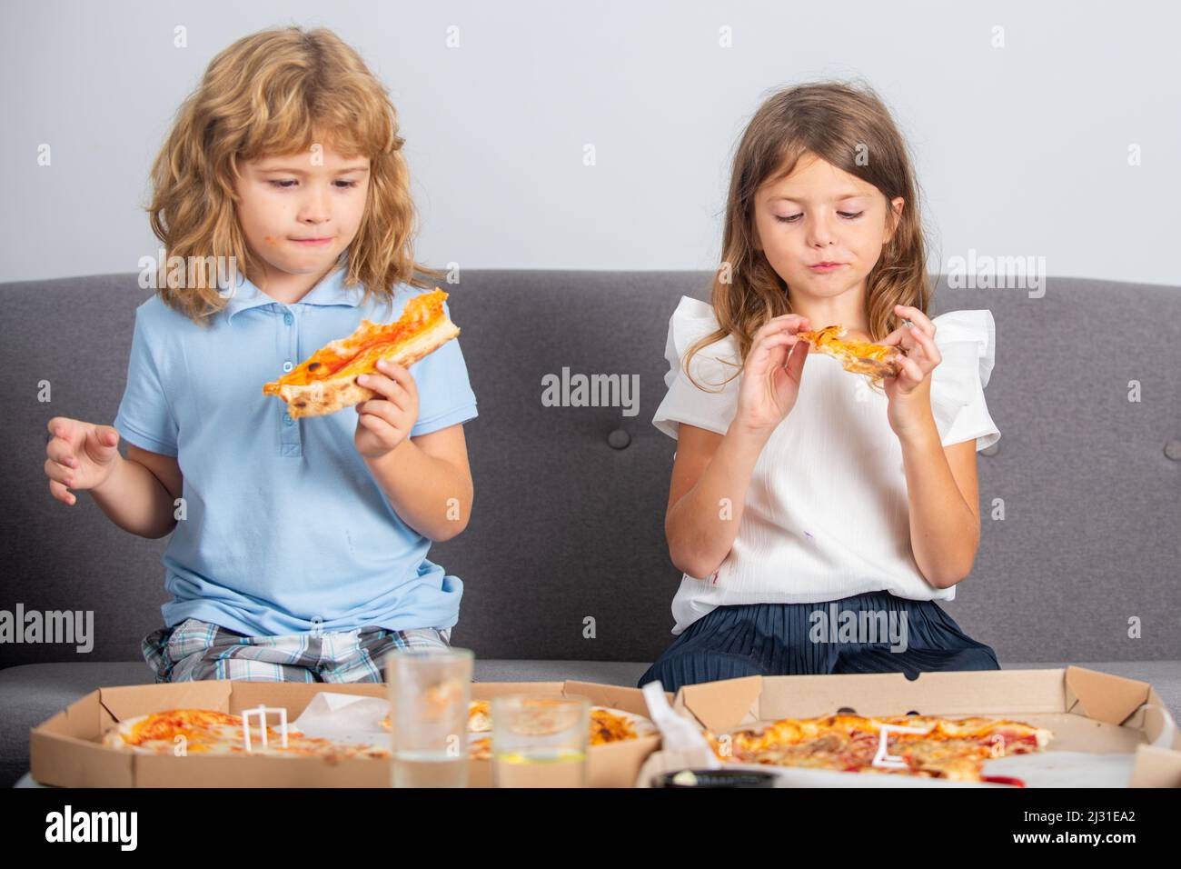 Funny kids eating pizza. Little girl and boy eat pizza Stock Photo - Alamy