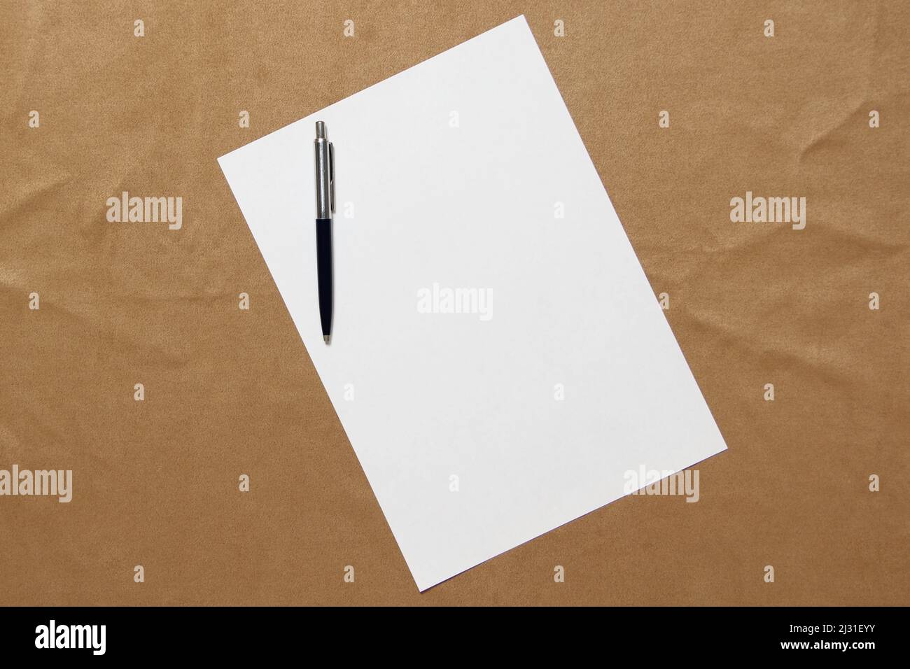 Template of white paper with pen lies diagonally on light brown cloth ...