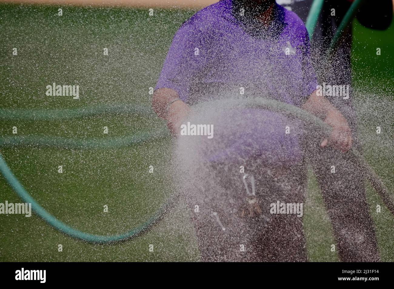 A groundskeeper sprays water on the infield dirt of a baseball diamond ...