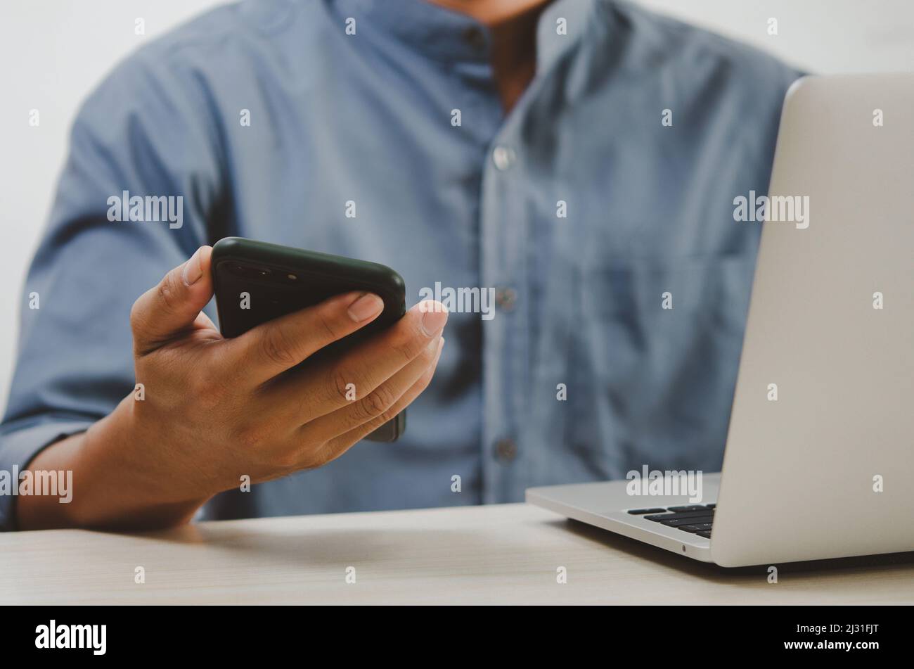 man using mobile smart phone and computer laptop searching internet, sending sms, using text ...
