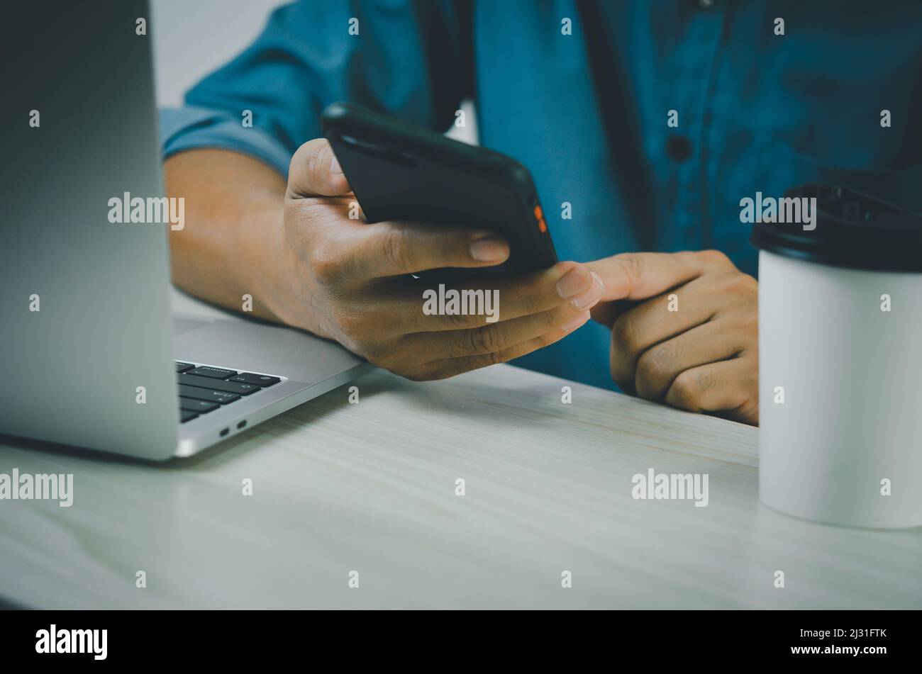 man hand holding smartphone and computer laptop to working technology searching internet ...