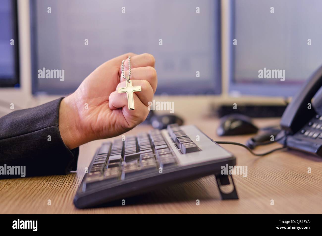 A businessman man with a religious Catholic cross in his hands is ...
