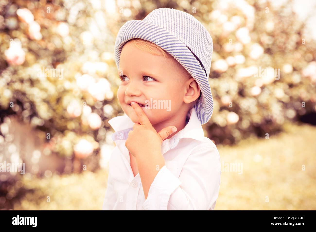 Close-up portrait of a little boy in spring park. Happy kid having fun ...