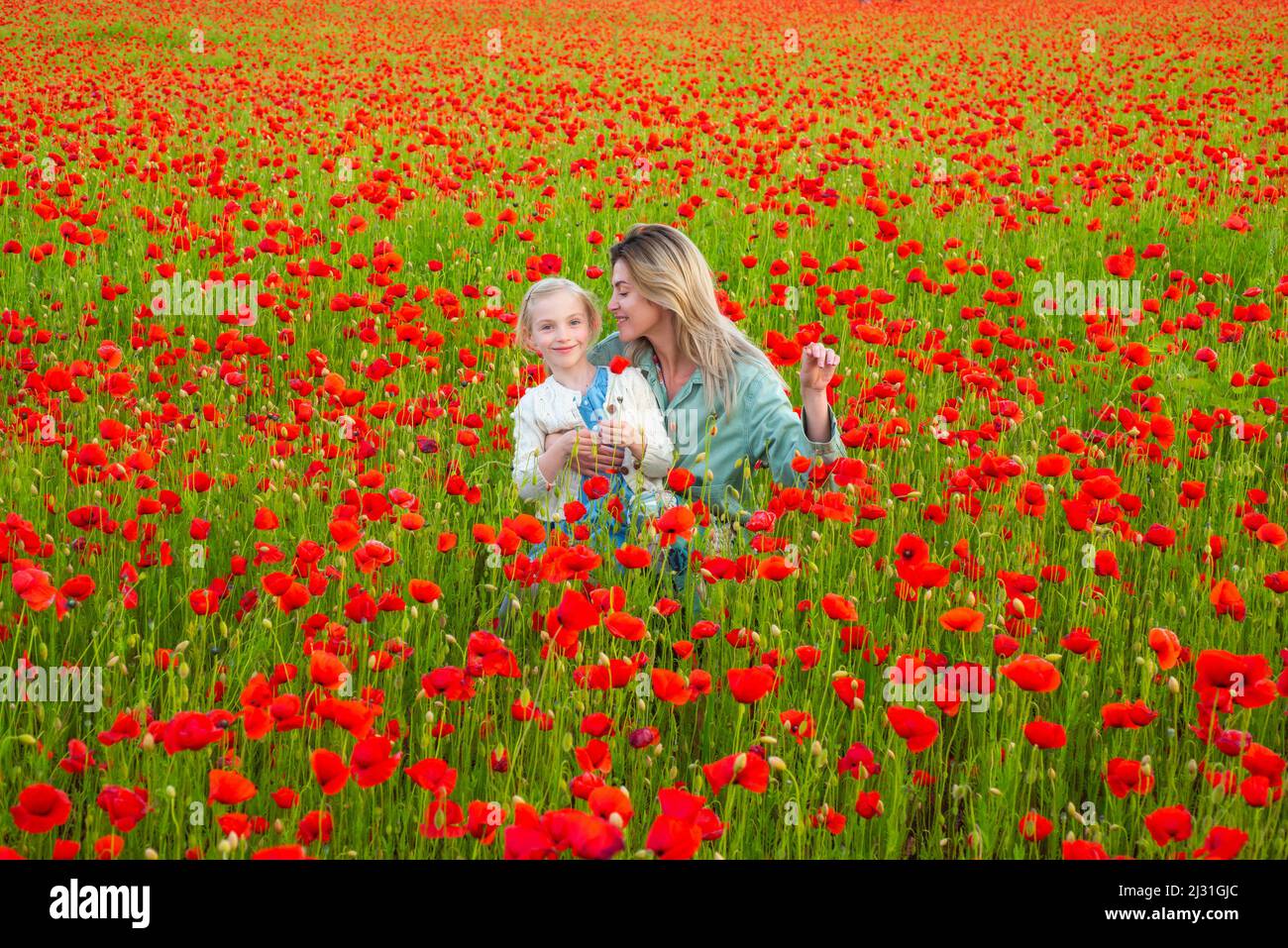 Mother with daughter outdoor in poppy field. Mom hugs lovely child on ...