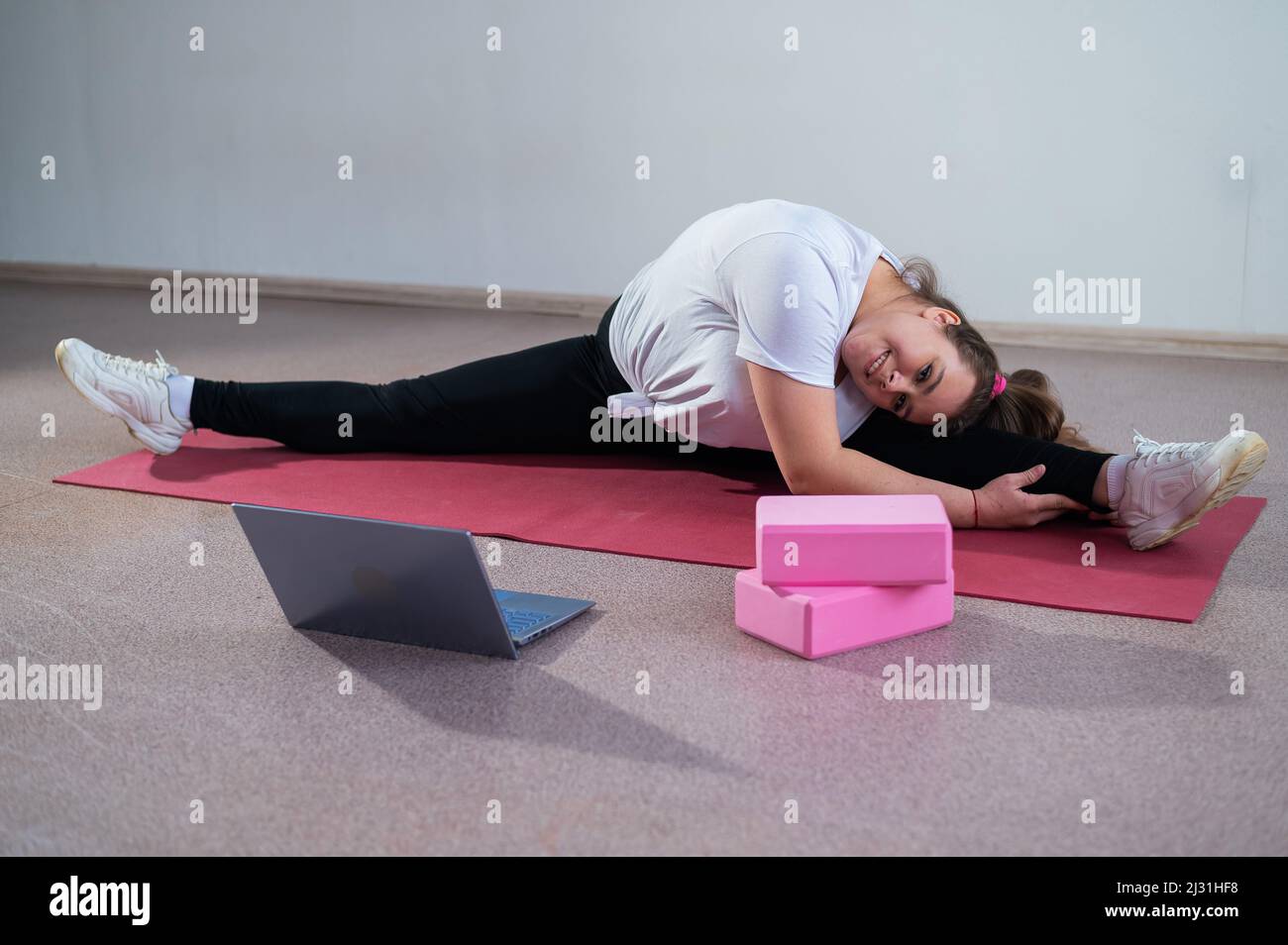 Young caucasian fat woman doing bends on a sports mat and watching a ...