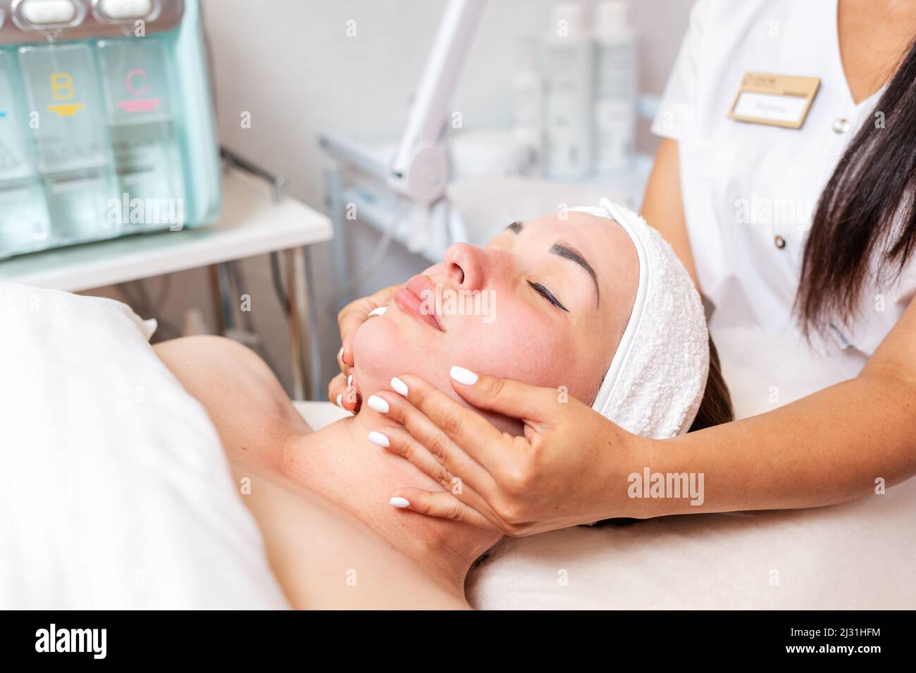 Cosmetologist makes a woman a facial massage procedure. Portrait of the client and the doctor's ...