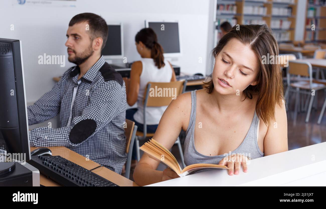 Female student with textbook in computer class Stock Photo - Alamy