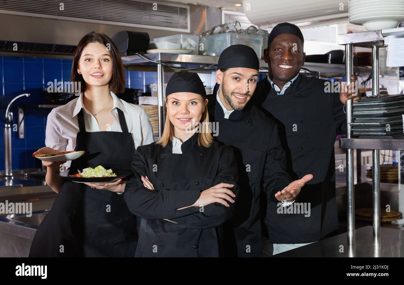 Woman waiter with command of cooks are posing together on kitchen in ...