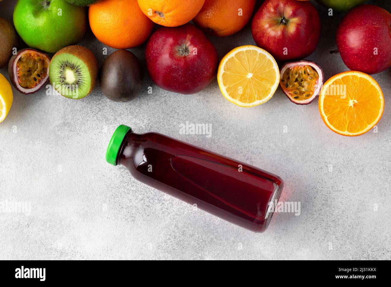 Various fruits and freshly squeezed fruits juice in bottle on gray ...
