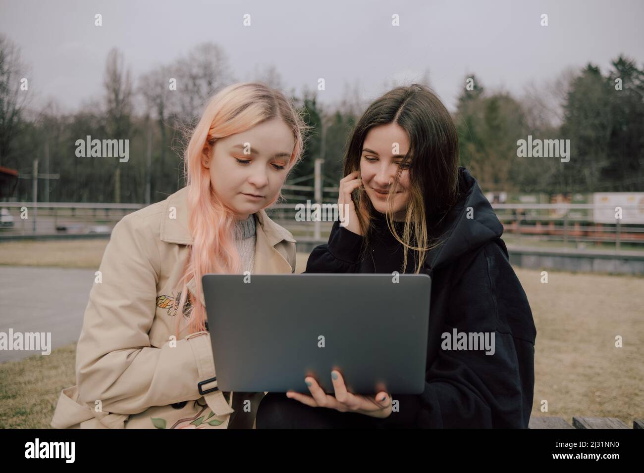 Two woman seat in the park with laptop and watch Stock Photo - Alamy