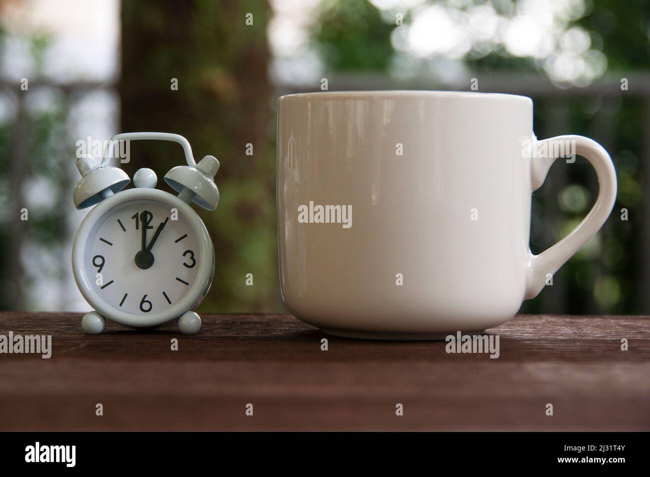 Alarm clock pointing at 1 o'clock with coffee cup on a bench. Copy ...