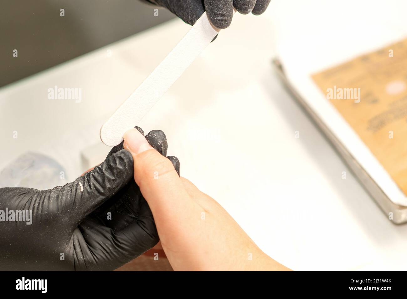 Close up of the caucasian hands of a professional manicurist are filing ...