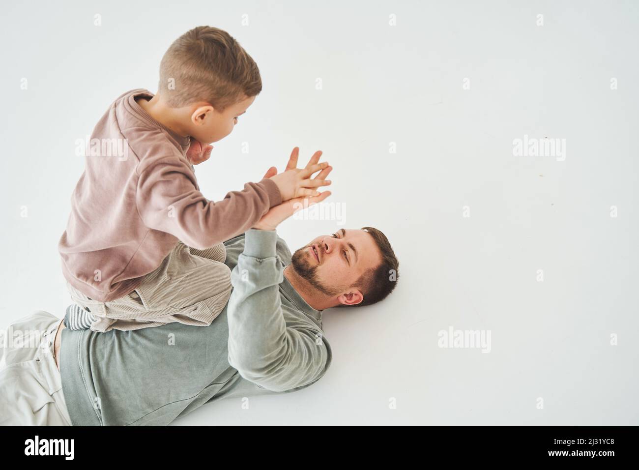 Father and son have fun and fool around together on white background ...