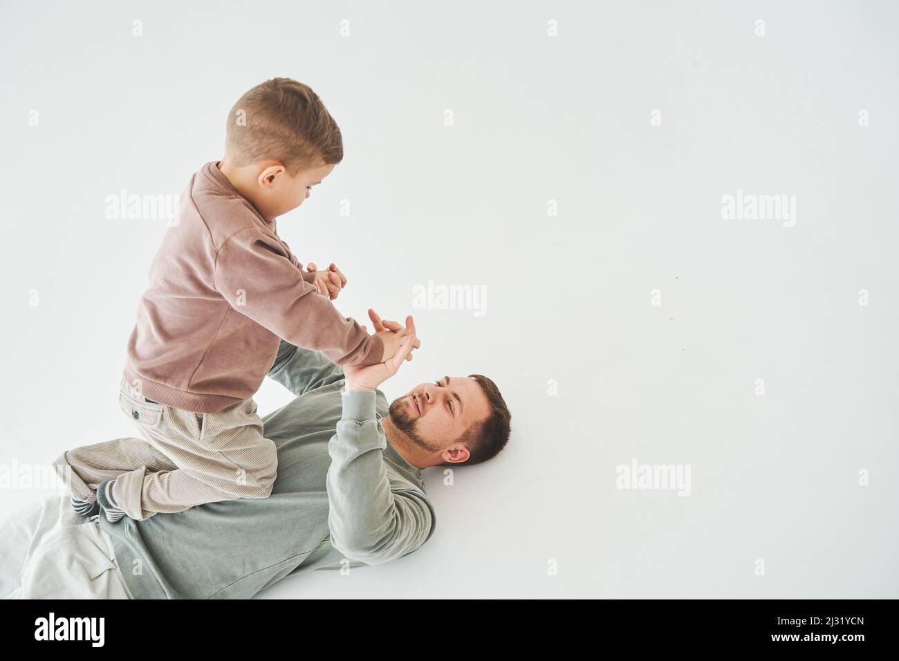 Father and son have fun and fool around together on white background ...
