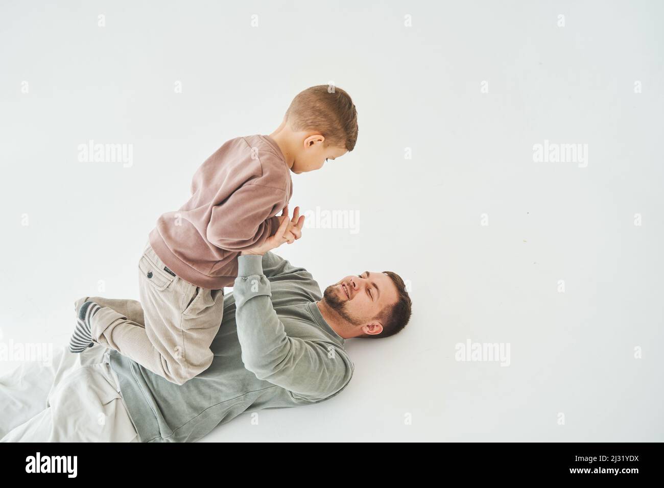Father and son have fun and fool around together on white background ...