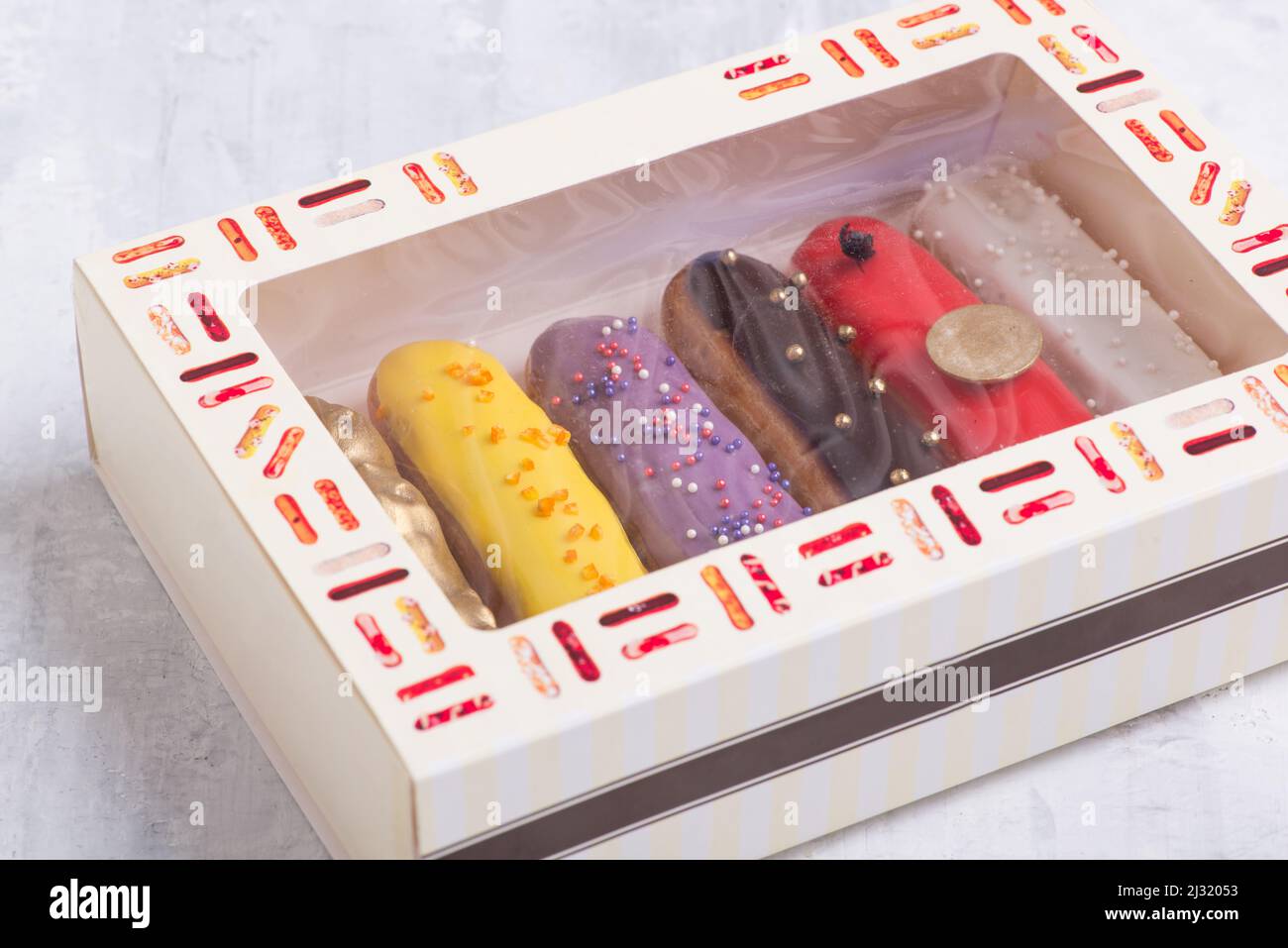 An angle shot of colorful glazed eclairs placed in a cute box with a ...