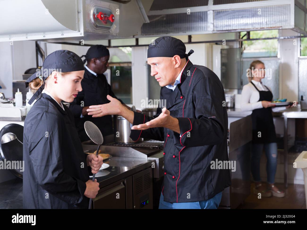 Exasperated chef scolding female employee Stock Photo - Alamy