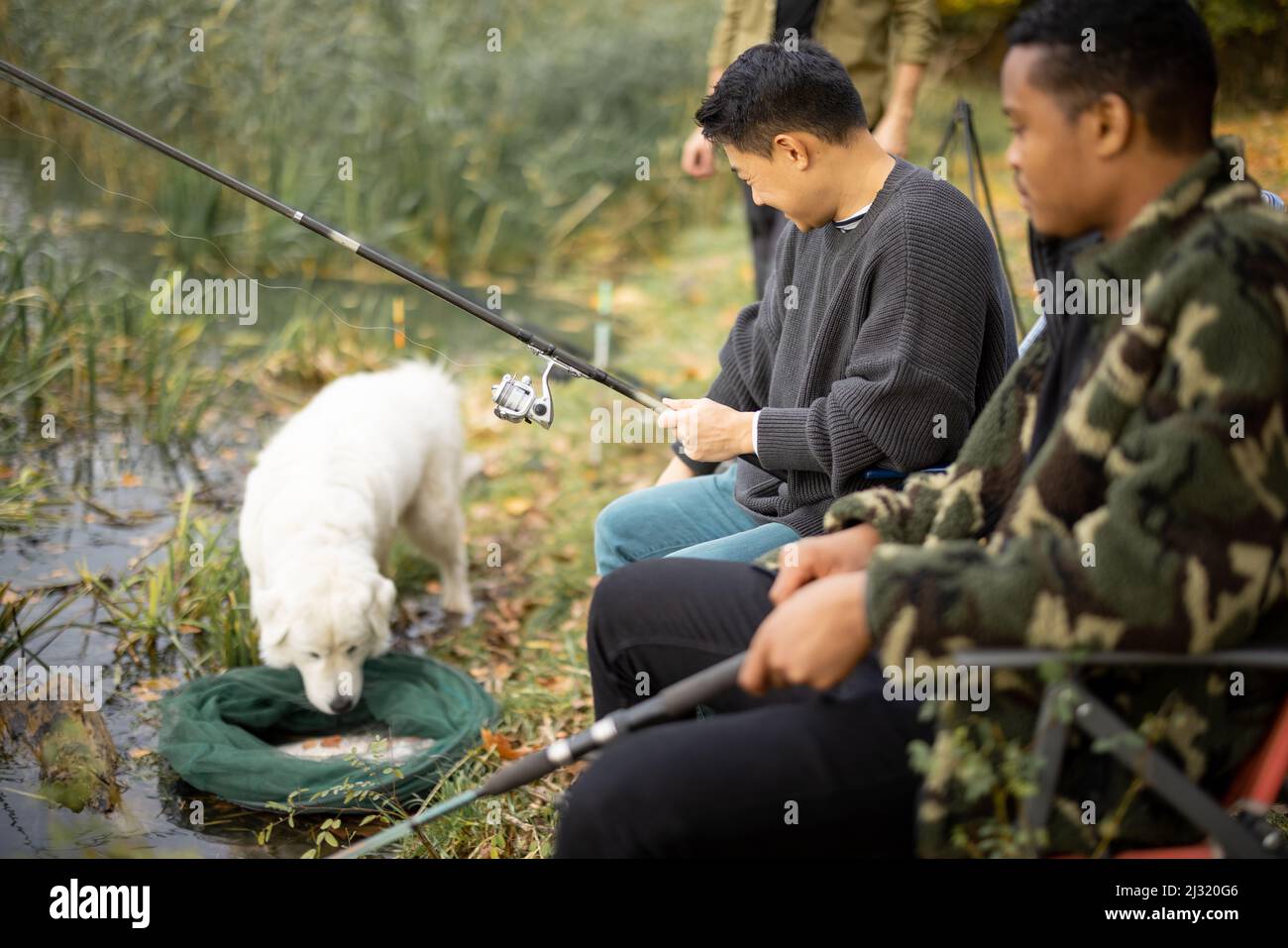 Male friends talking and fishing on lake coast Stock Photo - Alamy