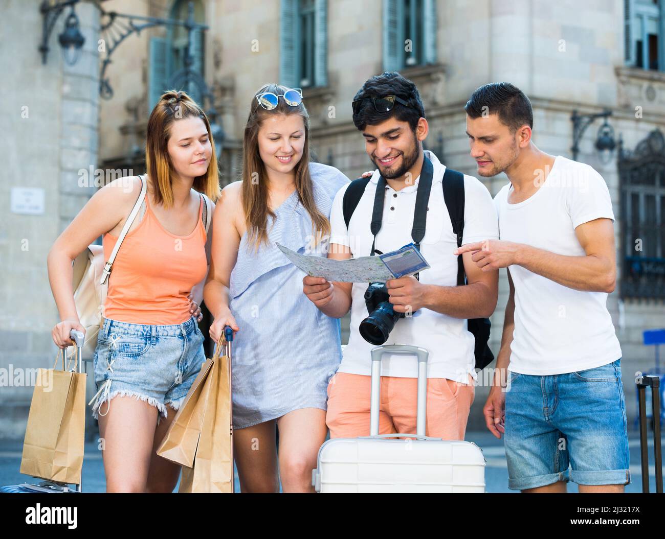 Four cheerful traveling young people with map Stock Photo - Alamy