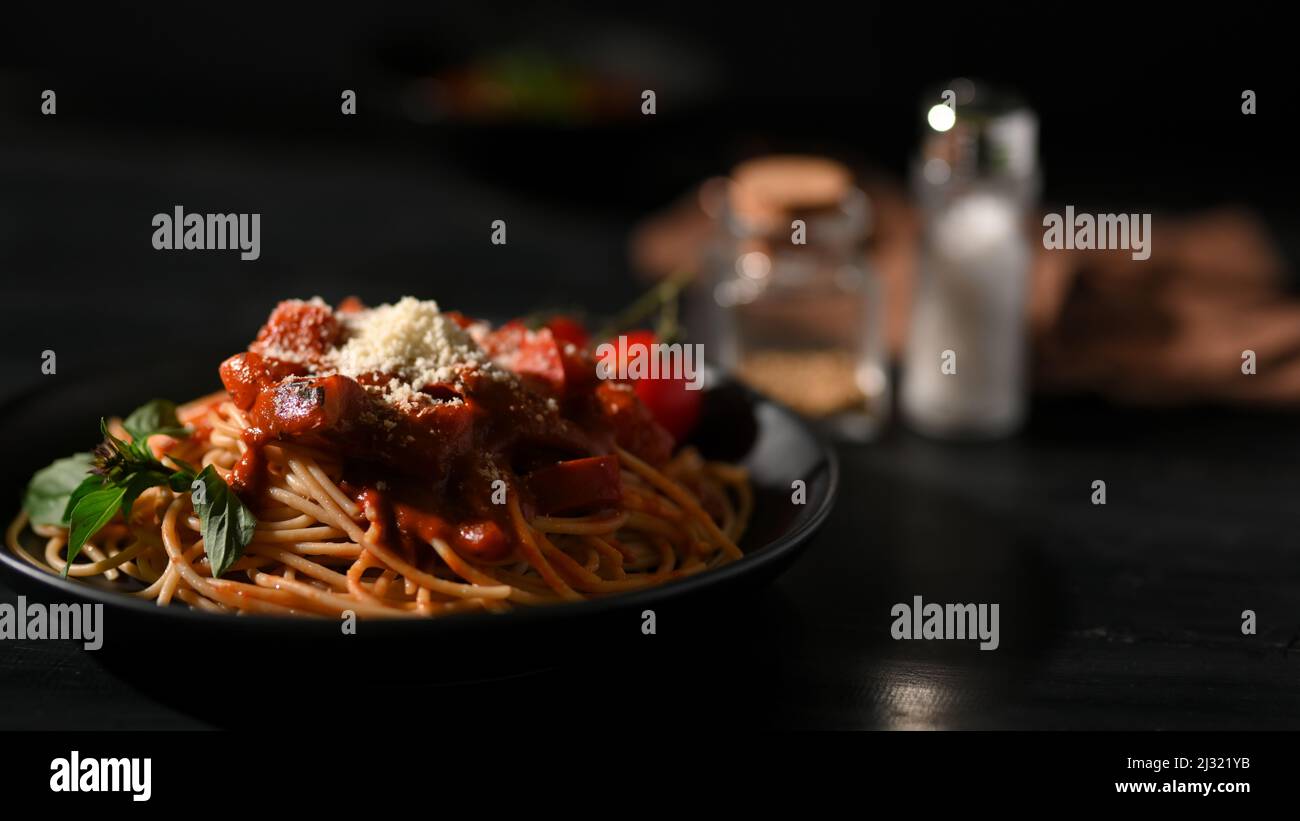 Spaghetti with tomato sauce topped with parmesan cheese in a black ...