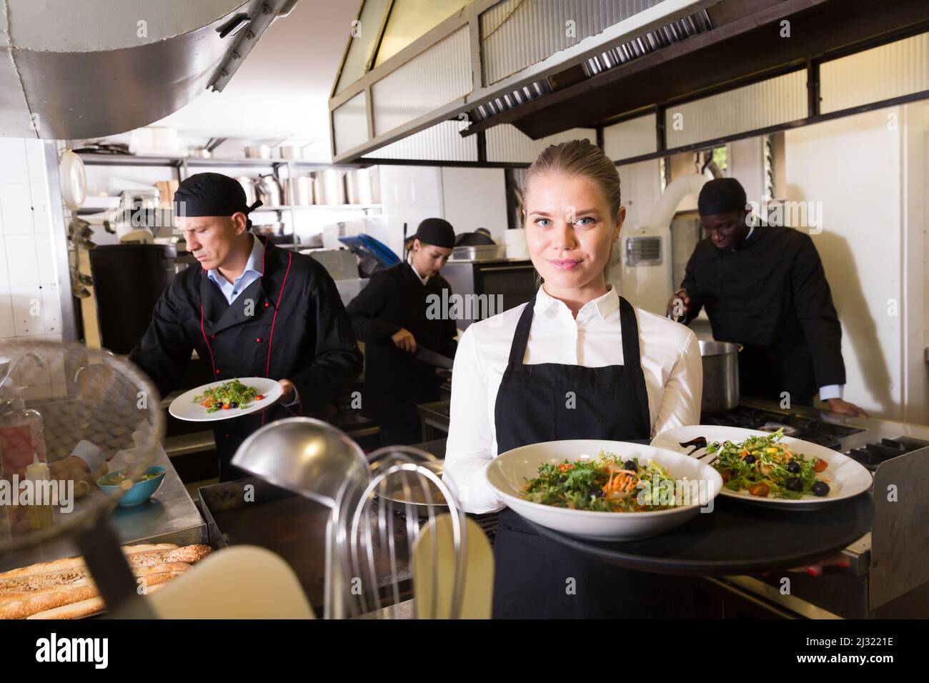 Waitress holding cooked meals in kitchen Stock Photo - Alamy