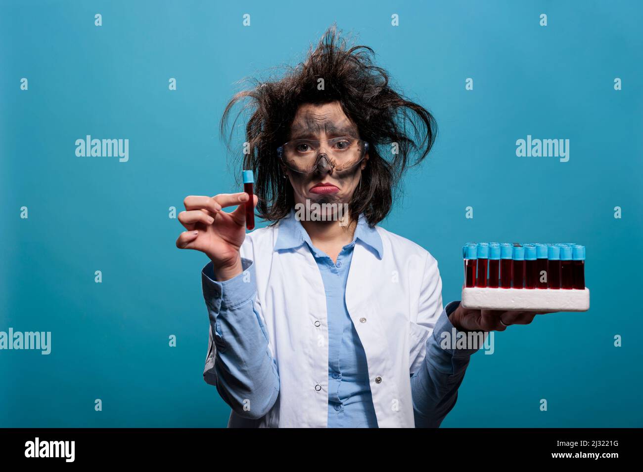 Sad mad scientist with messy hair and dirty face holding glass test ...