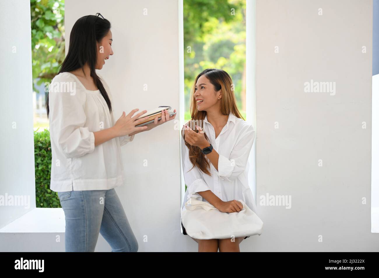 Two Asian female college students enjoy talking and laughing together ...