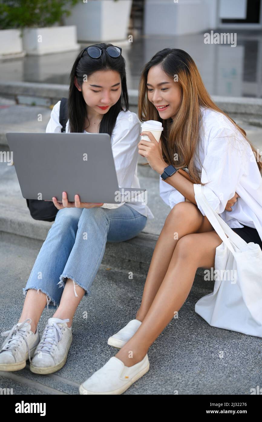 Two attractive Asian female college students sitting on the stairs ...