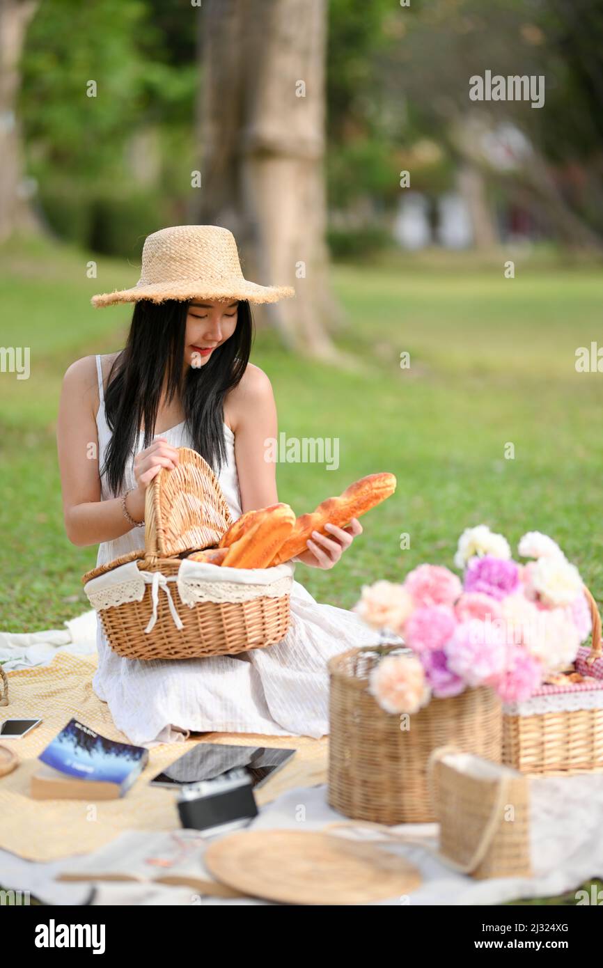 Charming Asian woman with a pretty dress, wicker picnic basket with ...