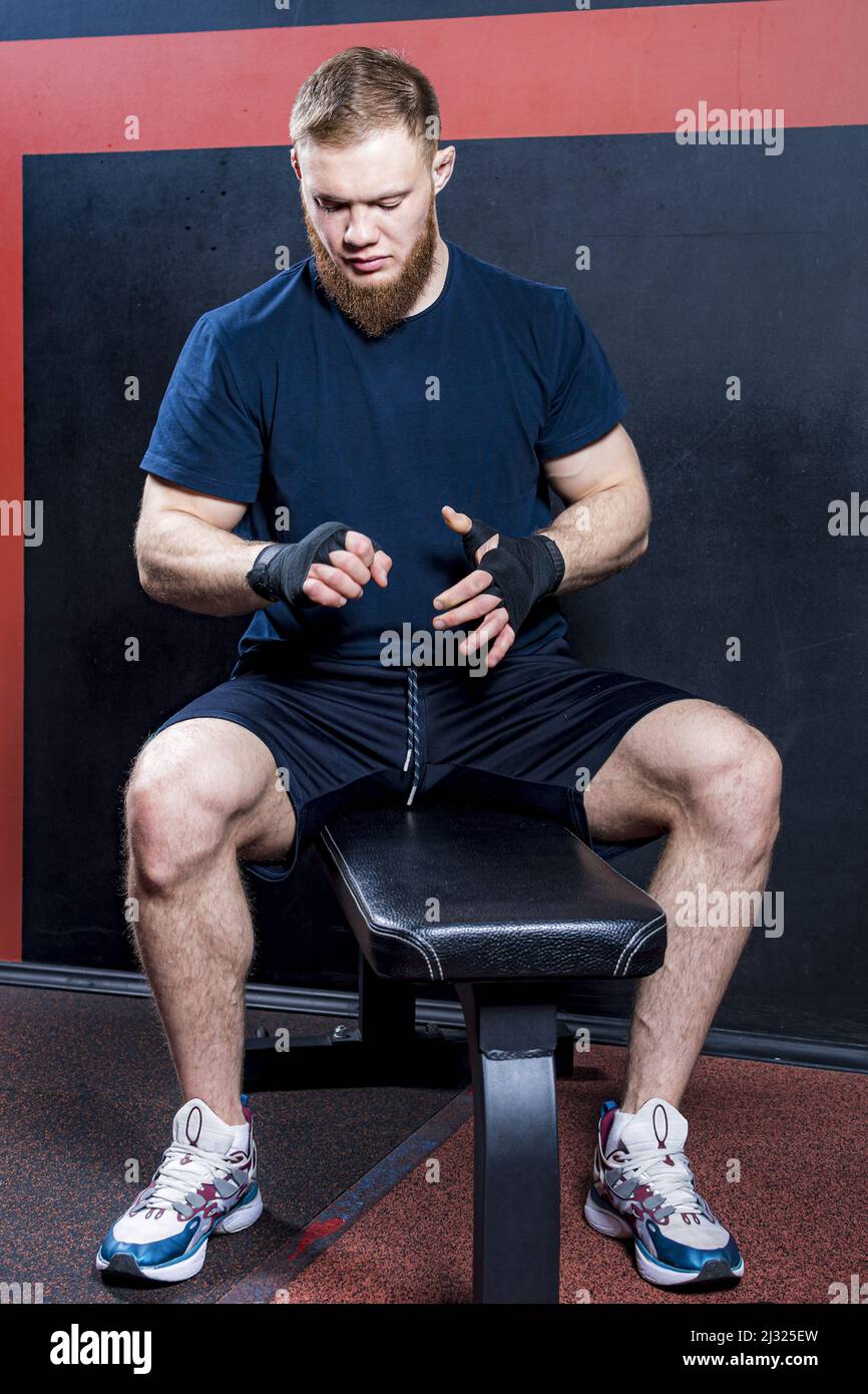 Young bearded mixed martial arts fighter sits on sports bench and ...