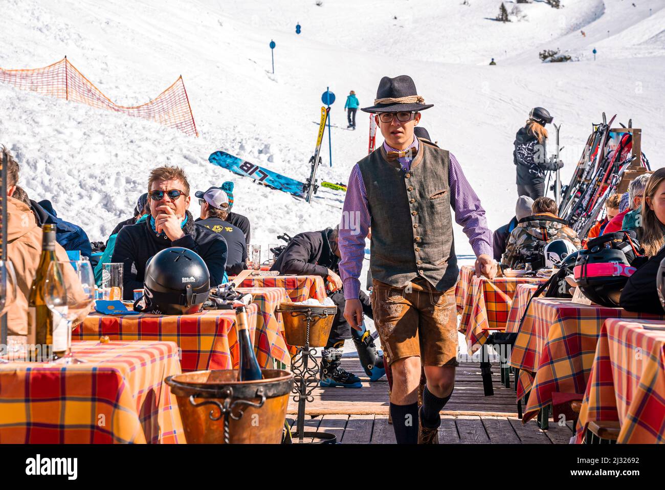 Waiter walking between people sitting on tables at mountain cafe on ...